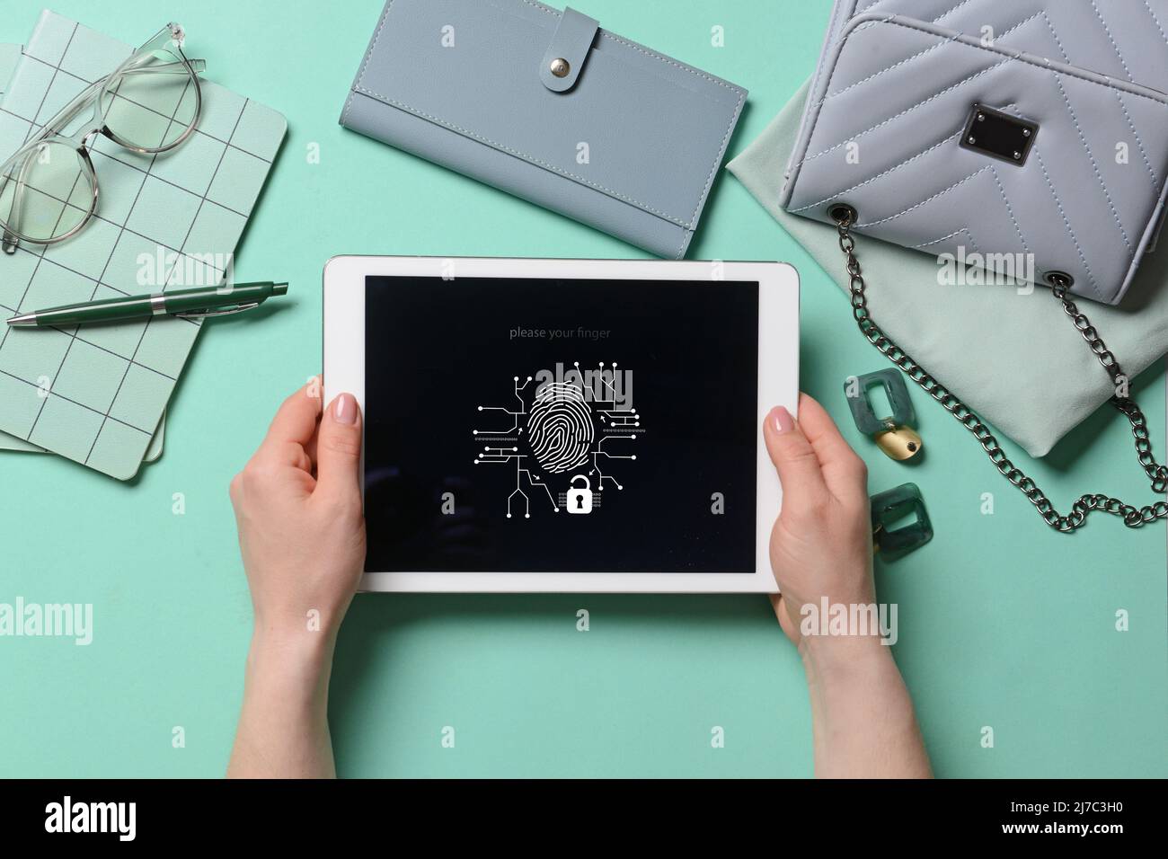 Hands holding tablet computer with locked screen against turquoise ...