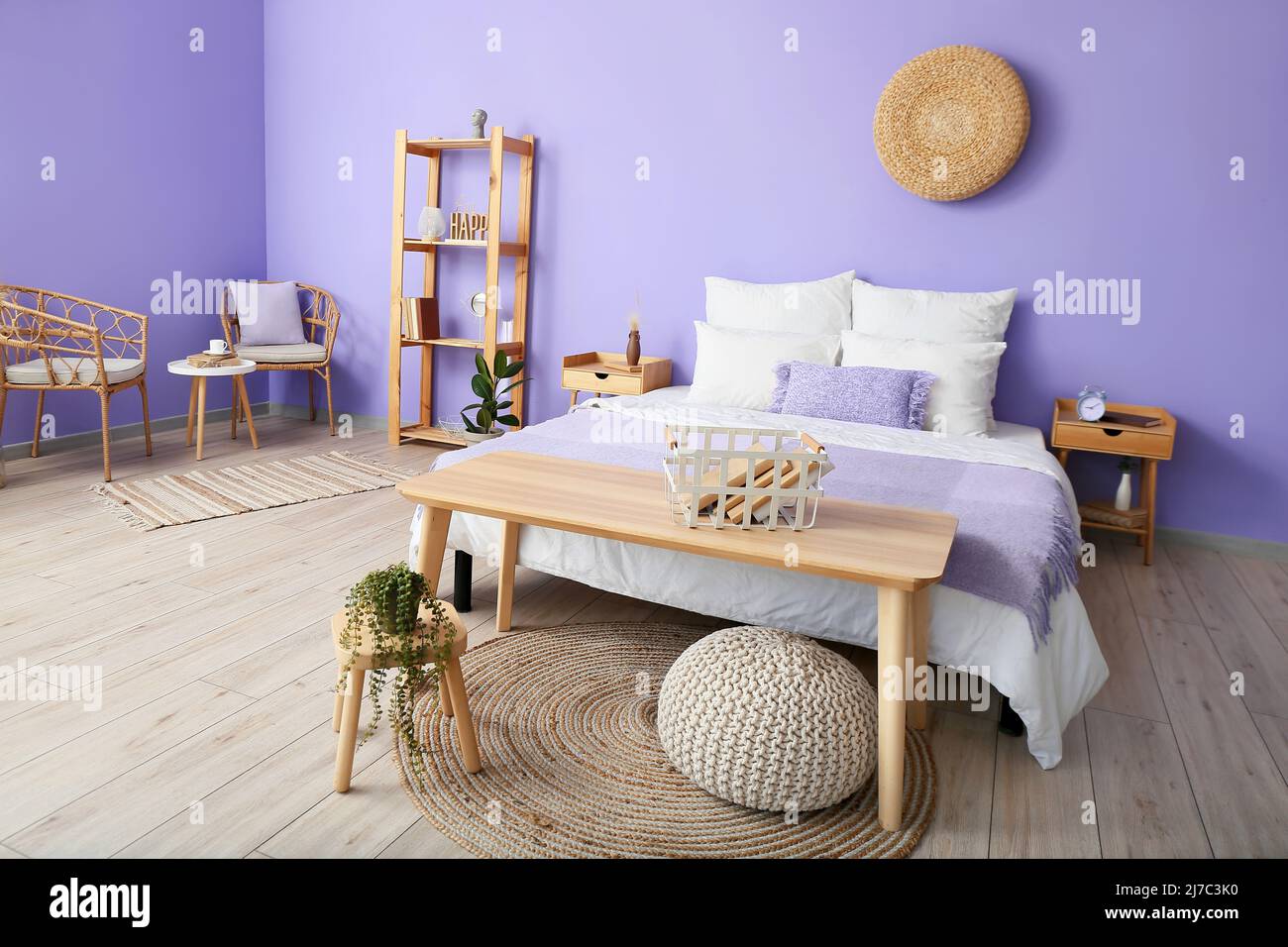 Interior of stylish room with bed, banquette, tables and shelf unit ...
