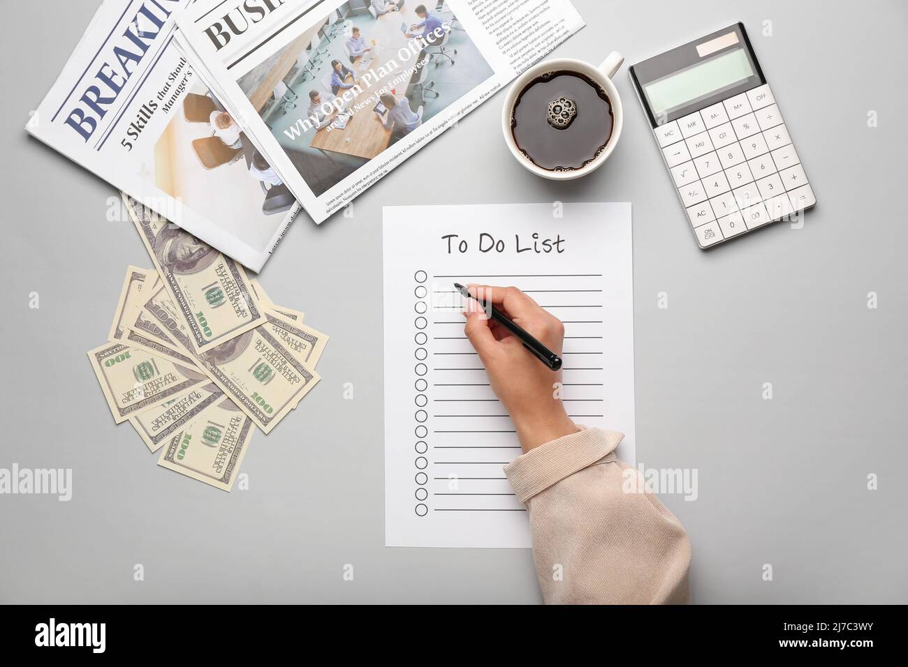 Female hand with to-do list, cup of coffee, newspapers and money on ...