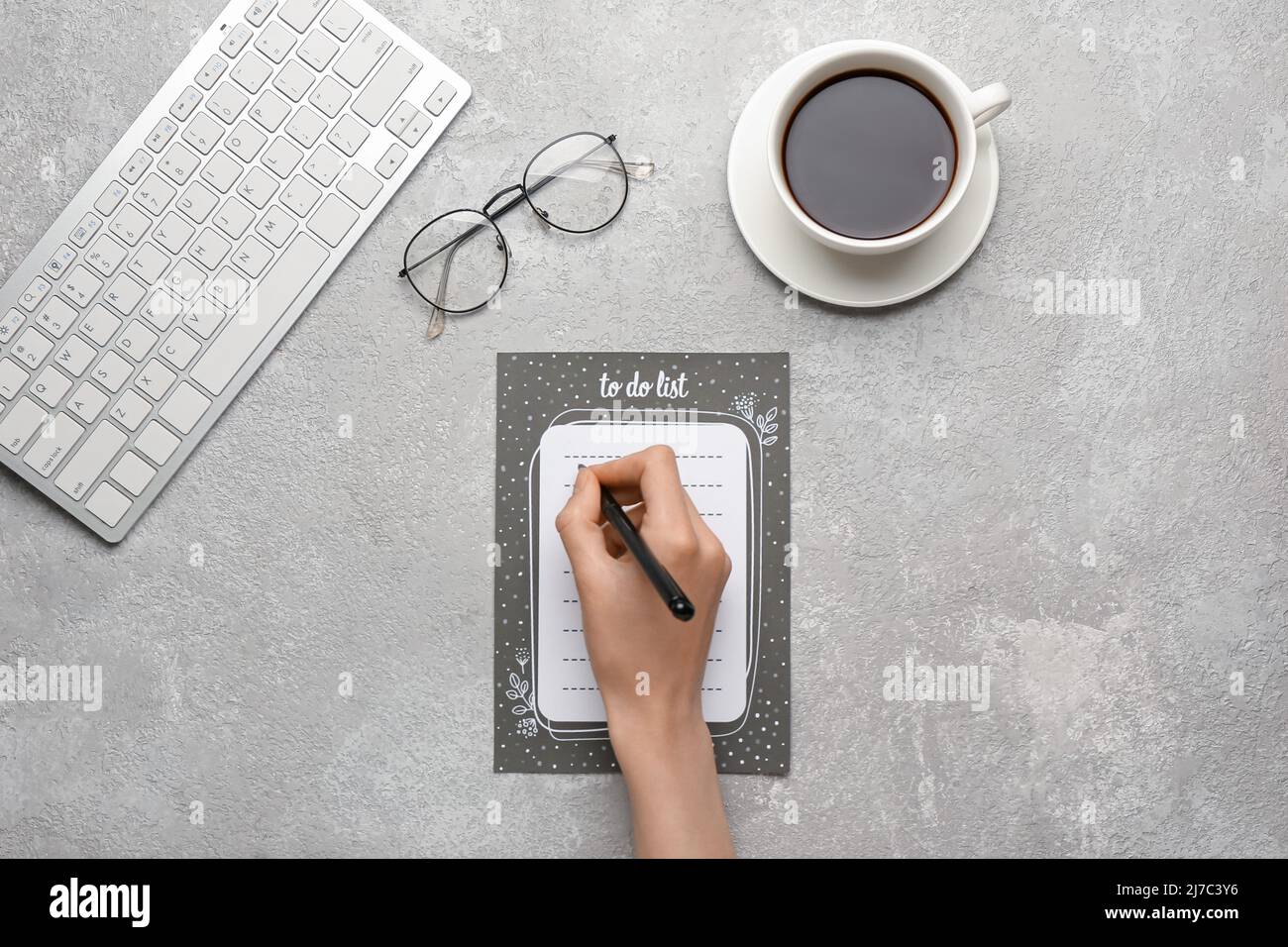 Female hand with to-do list, cup of coffee, keyboard and eyeglasses on ...