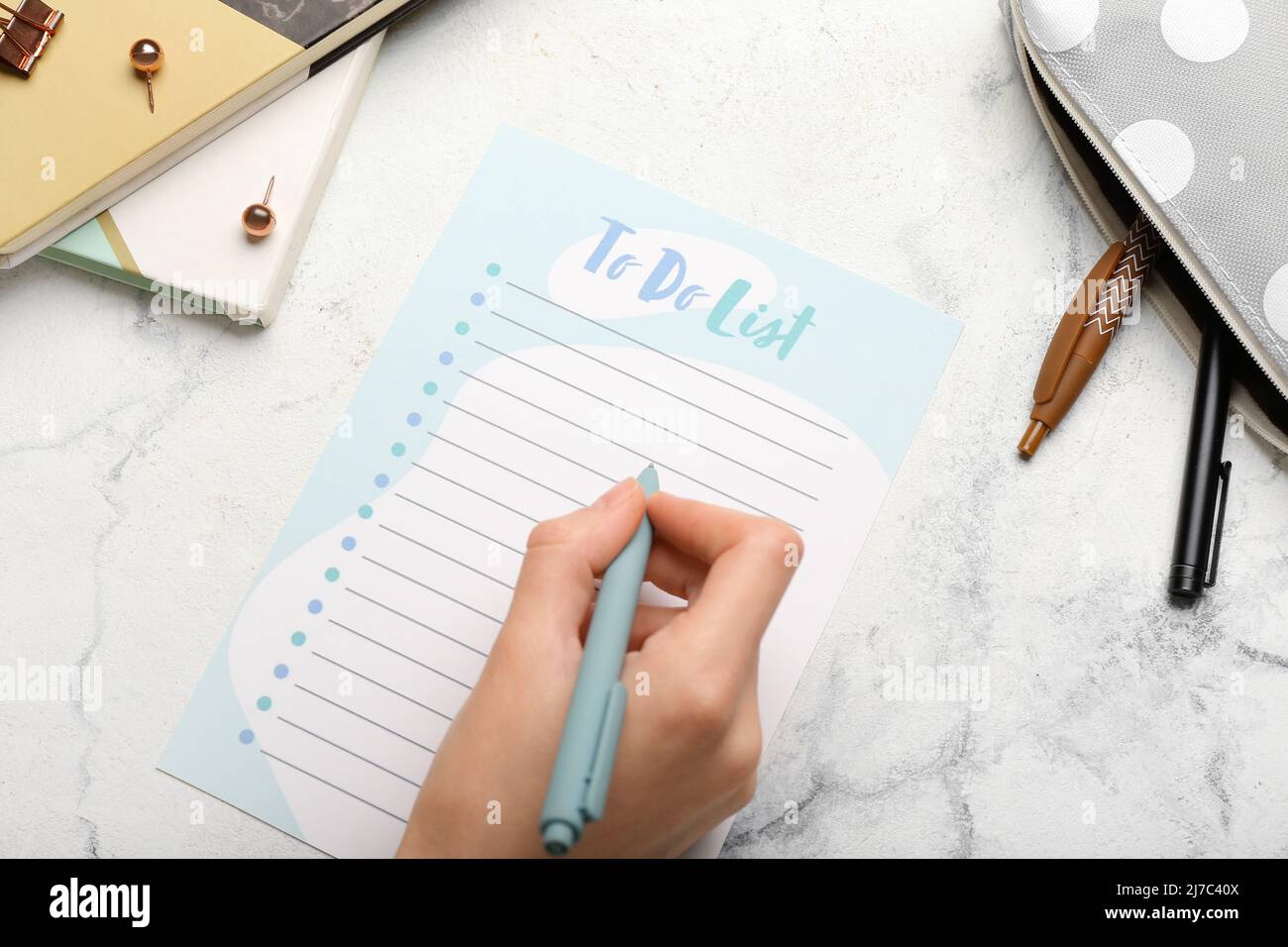 Female hand with to-do list and stationery on light background, closeup ...