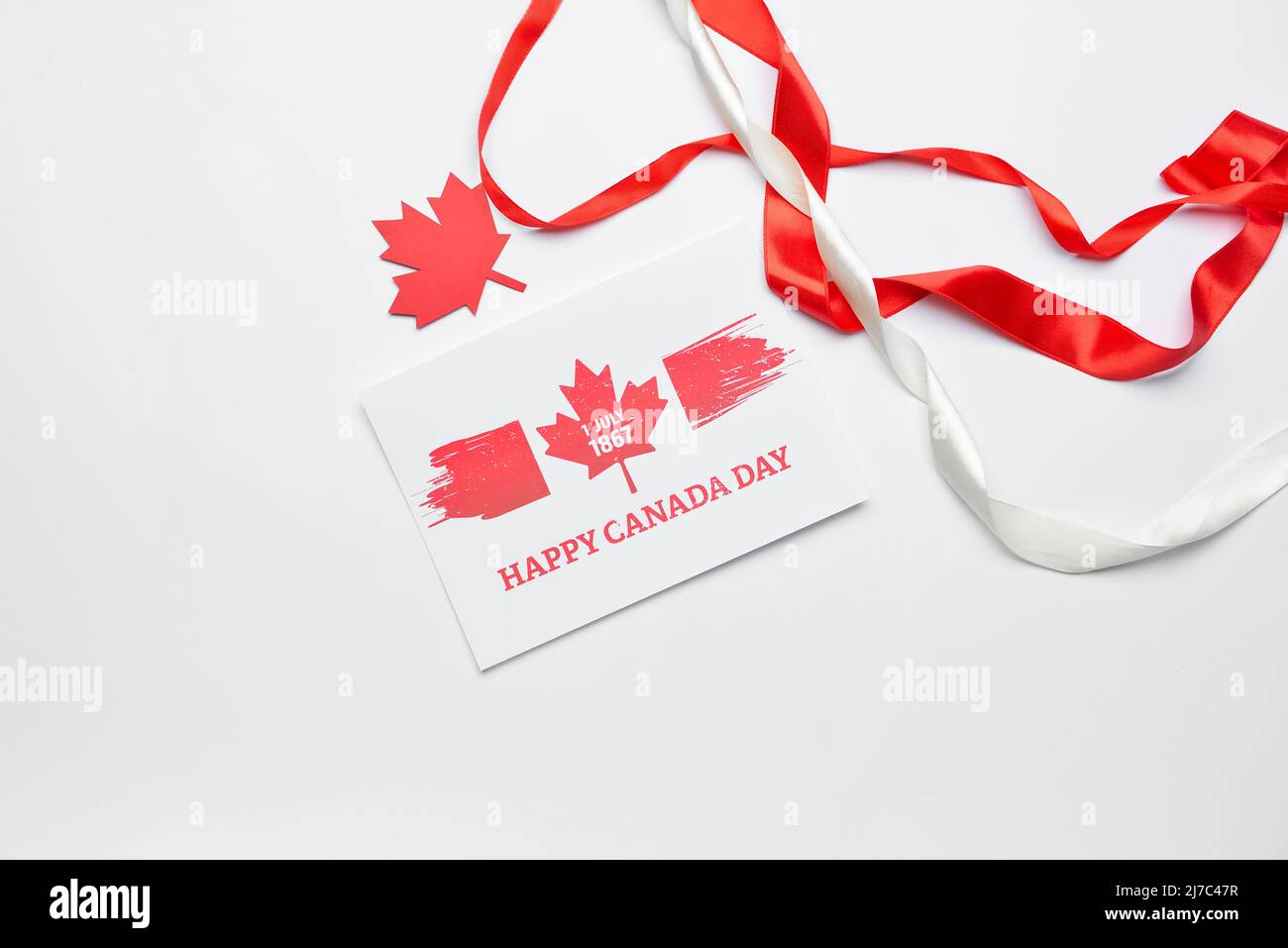 Ribbons, maple leaf and paper card with text HAPPY CANADA DAY on white ...