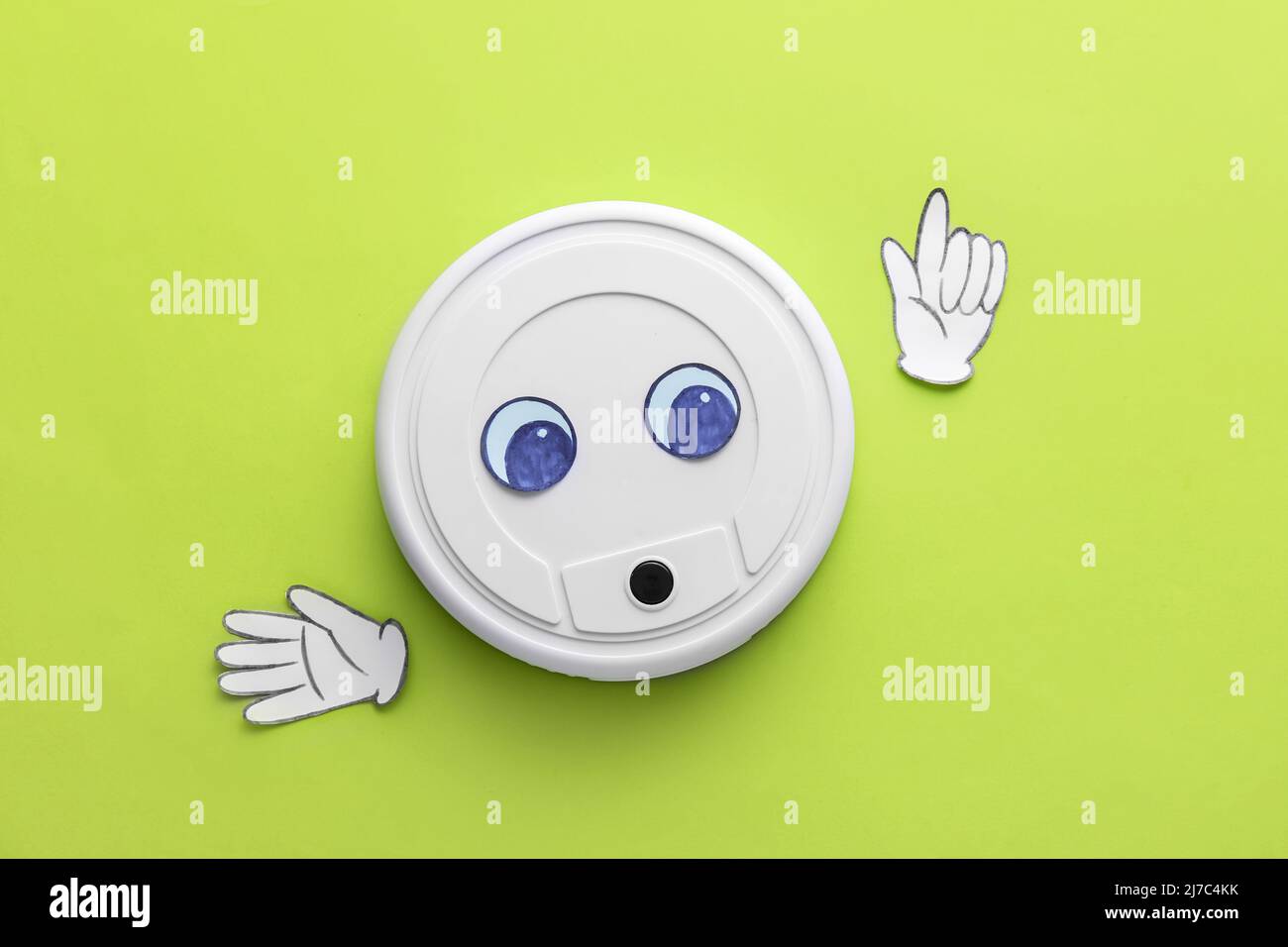 Modern robot vacuum cleaner with drawn eyes and paper hands on green ...