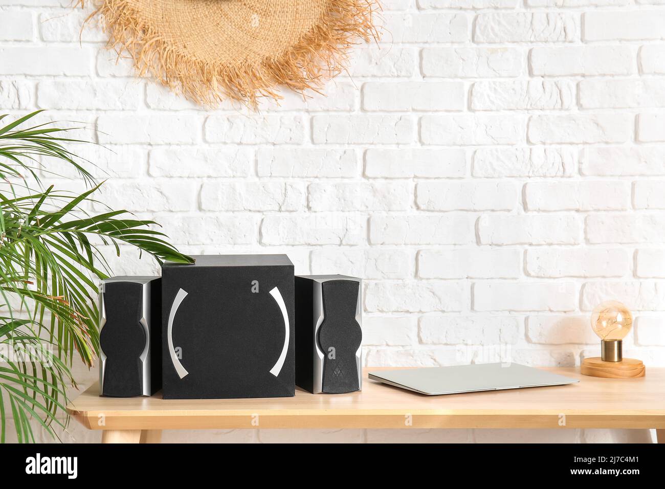 Speakers and modern laptop on table near white brick wall Stock Photo ...