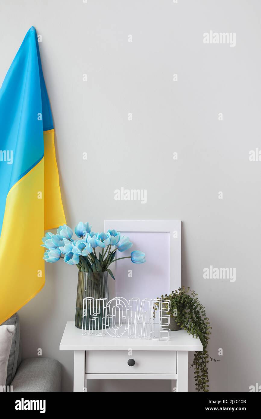 Vase with tulips, flag of Ukraine, decor, frame and houseplant on table ...