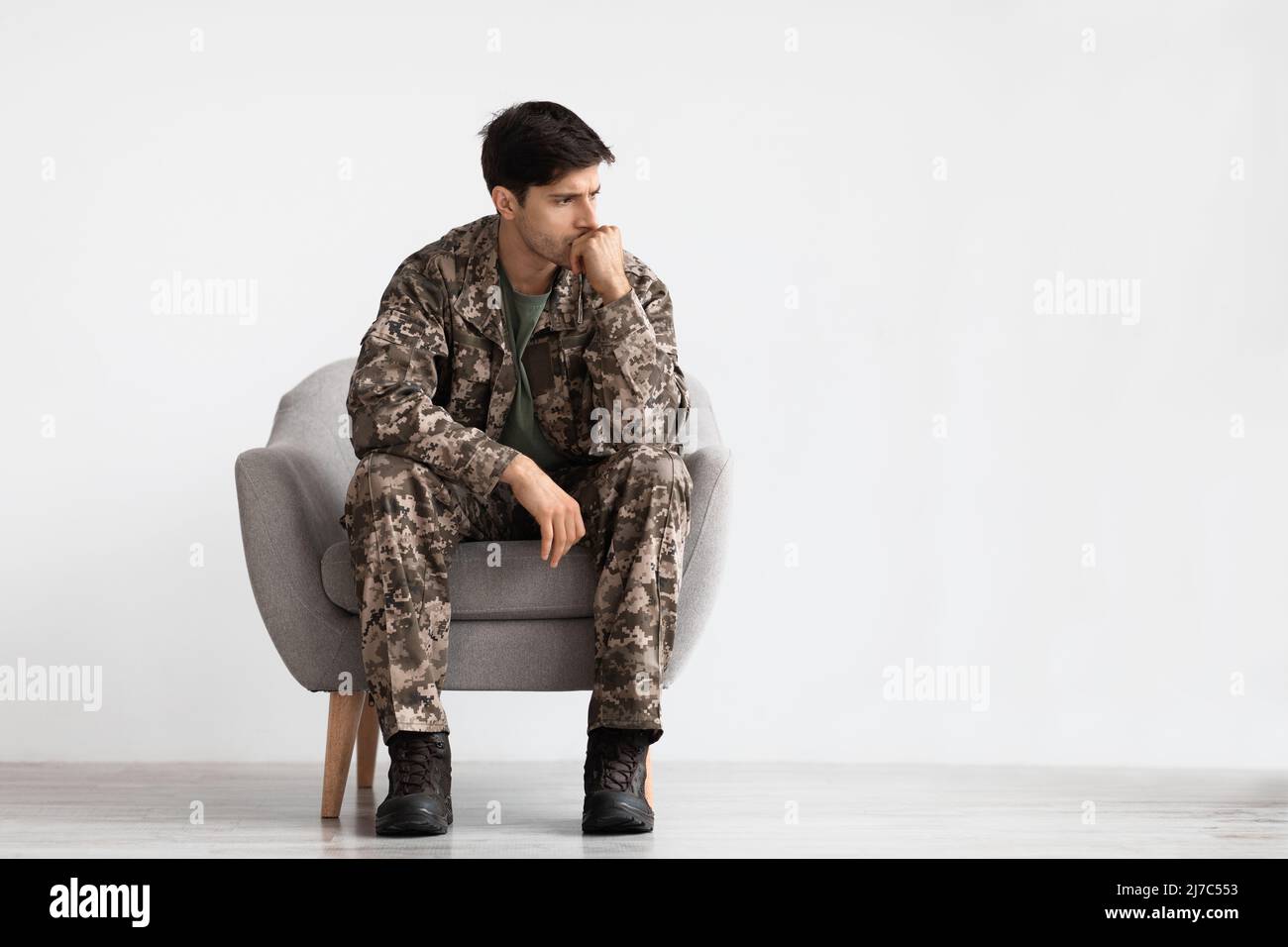 Pensive soldier sitting at armchair over white background Stock Photo ...