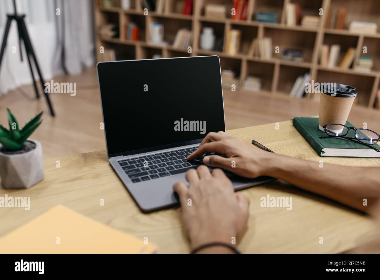 Unrecognizable Man Working On Laptop Computer With Blank Black Screen Typing On Keyboard