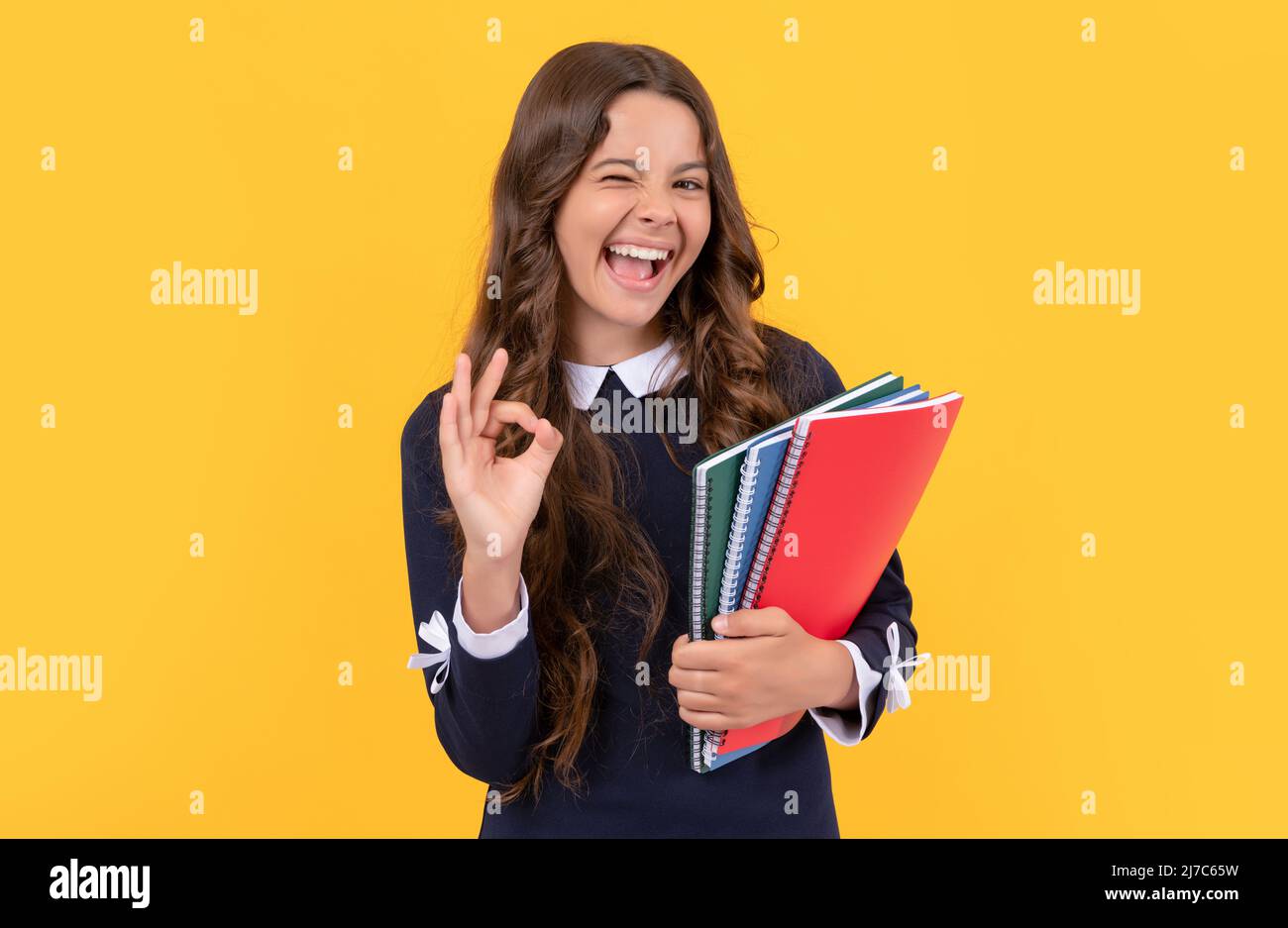 happy winking kid hold school copybooks studying on yellow background ...