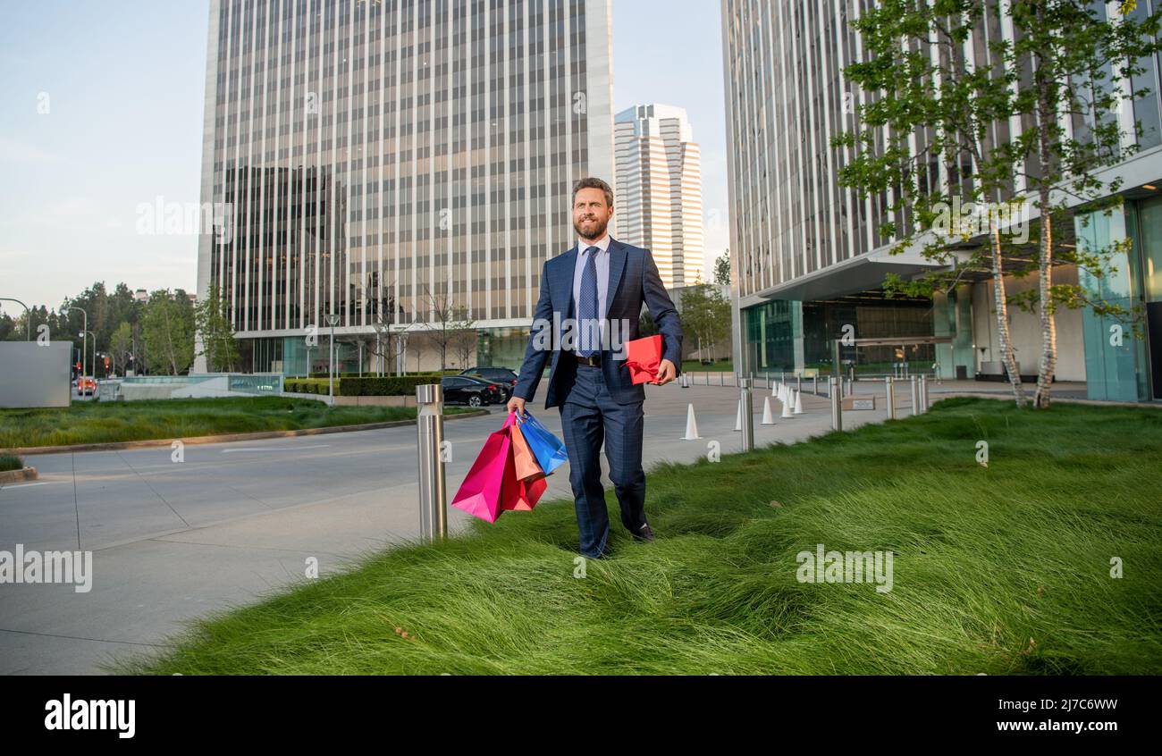 entrepreneur holding shopping bag and giftbox outside the office, full ...