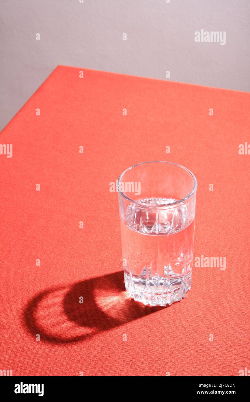 Glass of water with hard shadow on a table with red cloth Stock Photo ...