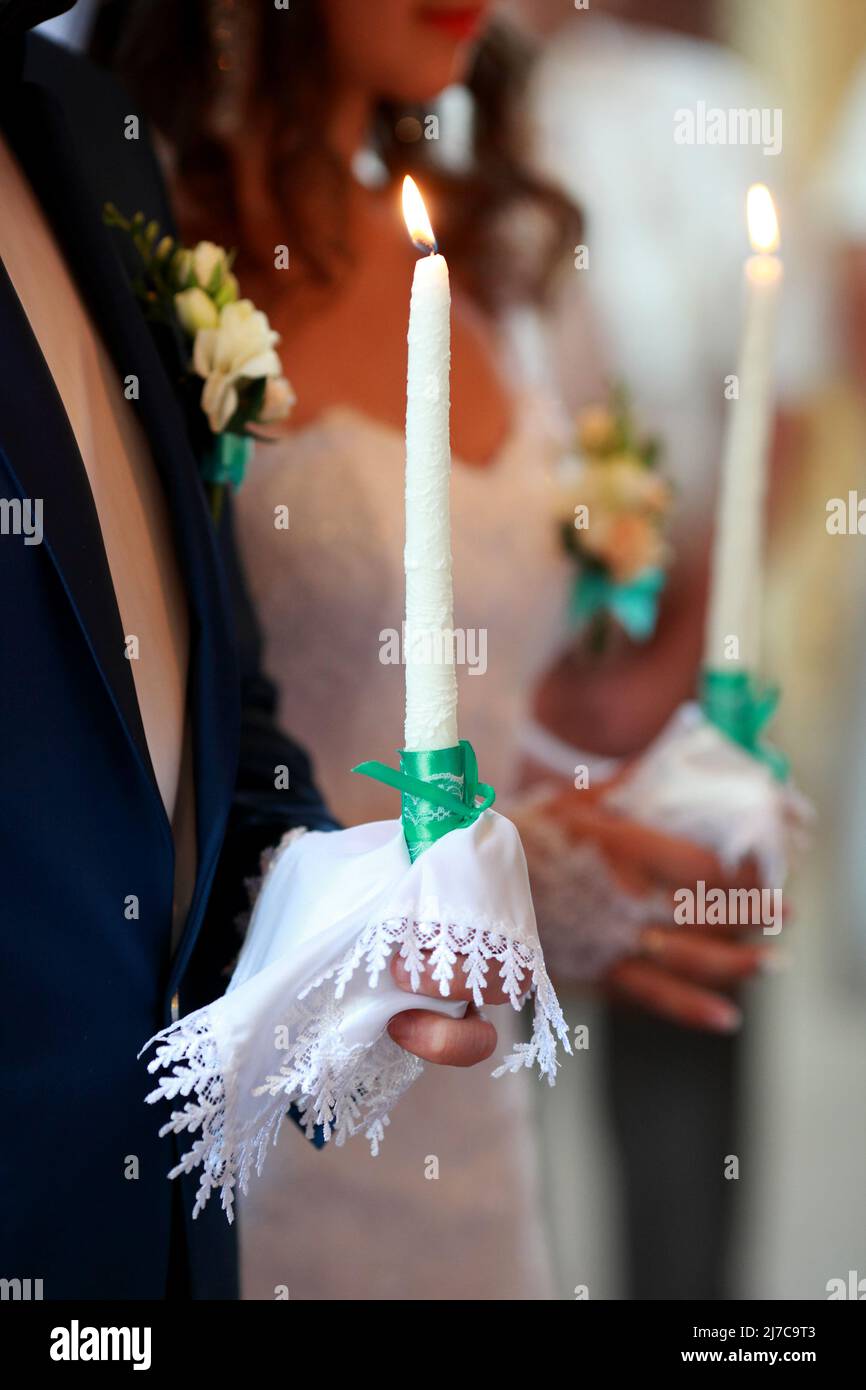 gorgeous bride and stylish groom holding candles at official wedding ...