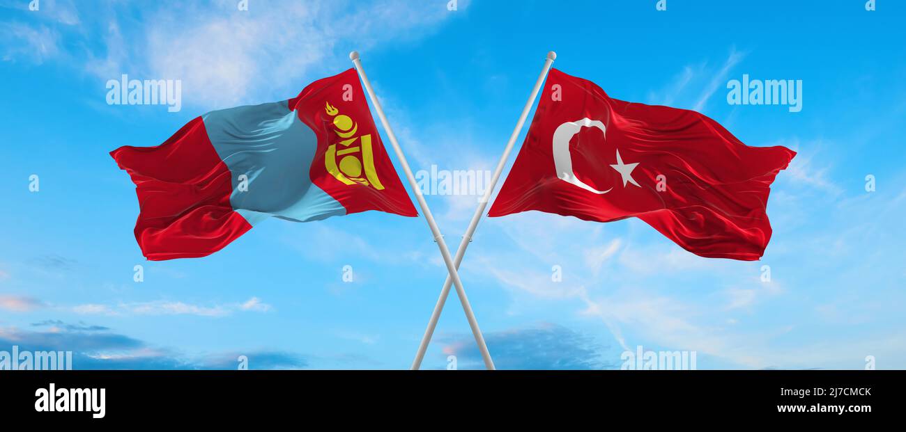 two crossed flags Mongolia and Turkey waving in wind at cloudy sky ...