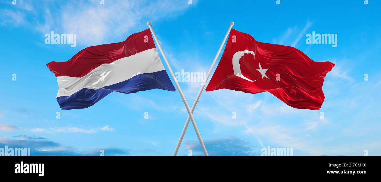 two crossed flags netherlands and Turkey waving in wind at cloudy sky ...