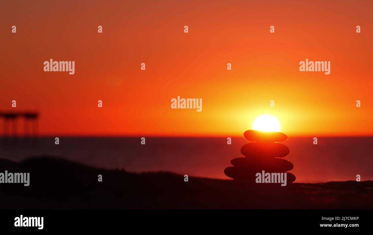 Stack of pebble stones, sandy ocean beach, sunset sky. Rock balancing ...