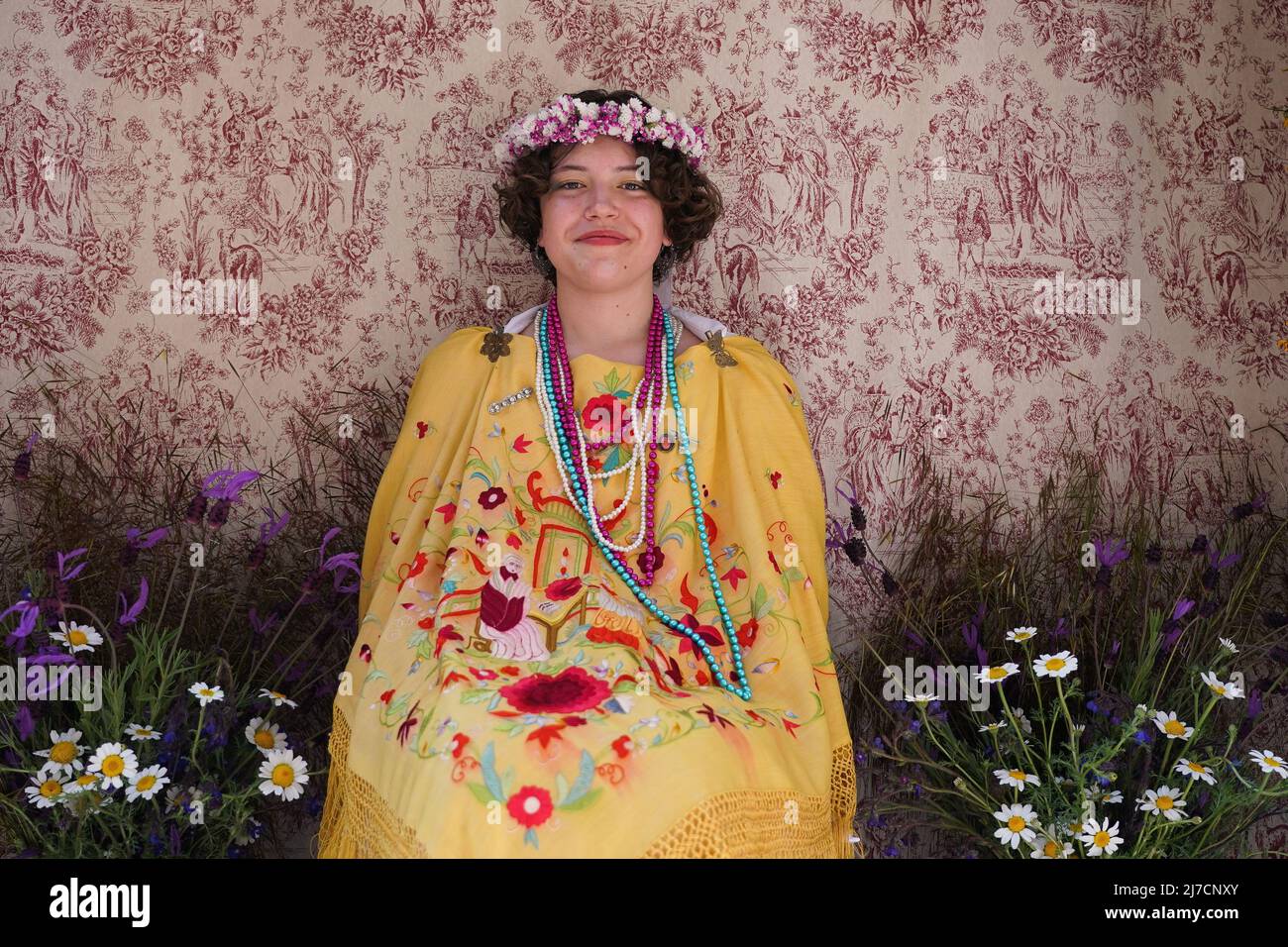 A girl, La Maya, sits on an altar during the celebration of La Maya ...