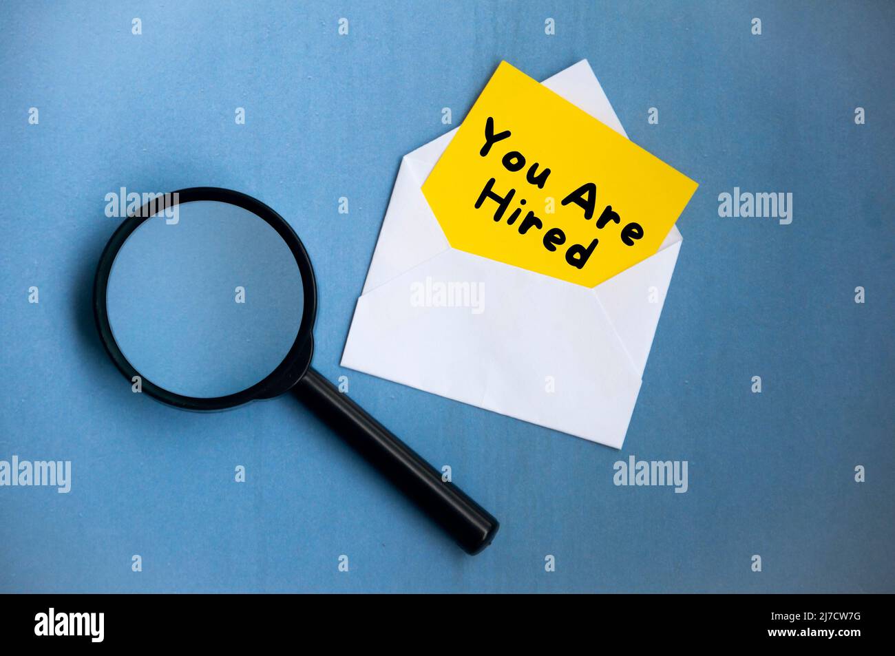 You are hired text on notepad in an envelope with magnifying glass on ...