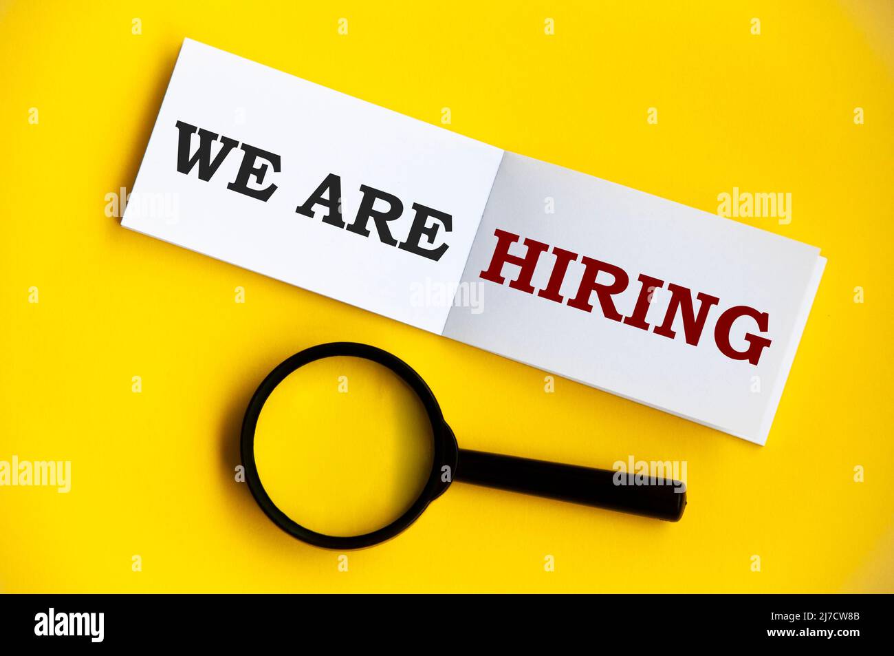 We are hiring text on notepad magnifying glass on yellow background ...