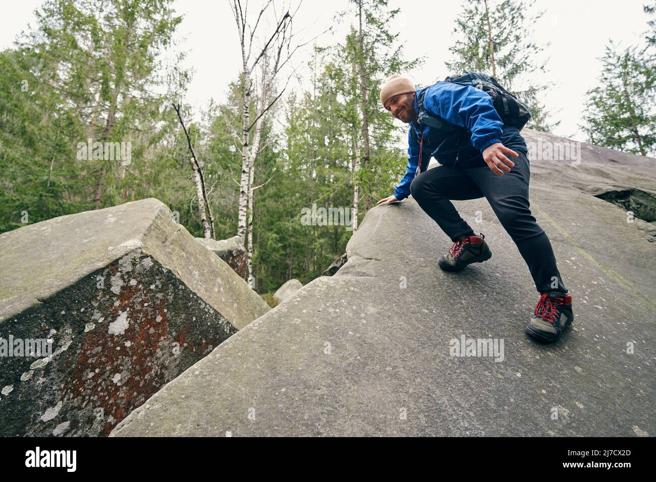 Male tourist holding rock edge while sliding down Stock Photo - Alamy