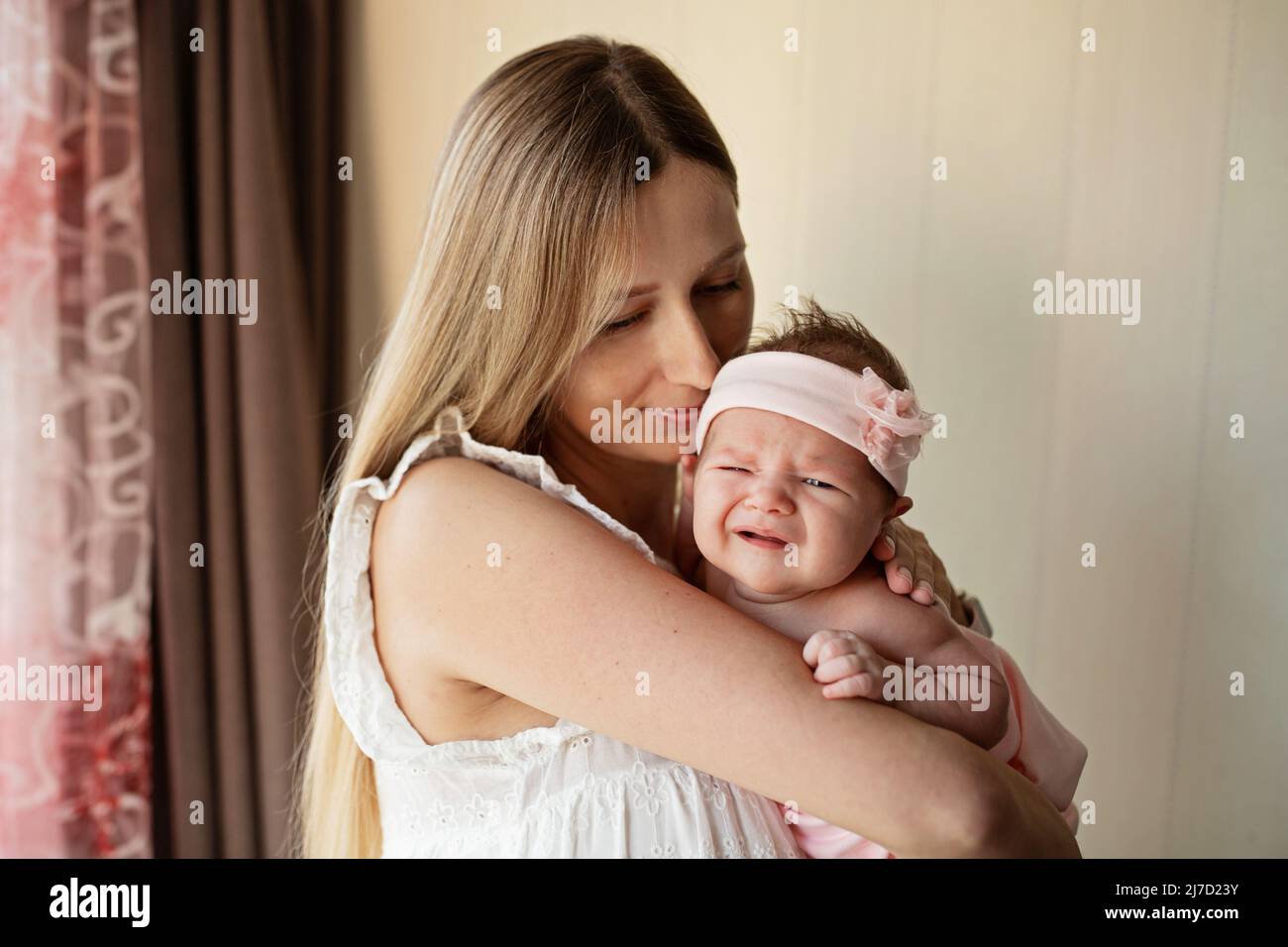 Portrait of young Caucasian mother holds hug little newborn baby two ...