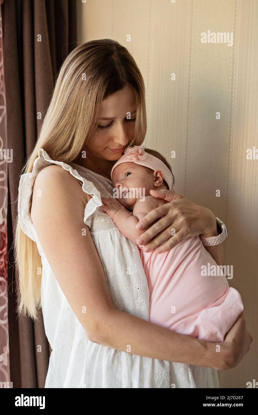Portrait of young Caucasian mother holds hug little newborn baby two ...