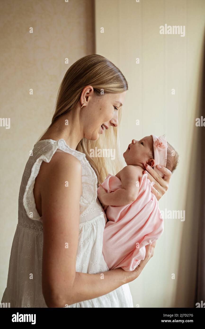Portrait of young Caucasian mother holds hug little newborn baby two ...