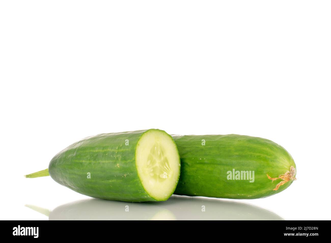 One whole and one half of a juicy smooth cucumber, macro, isolated on a ...