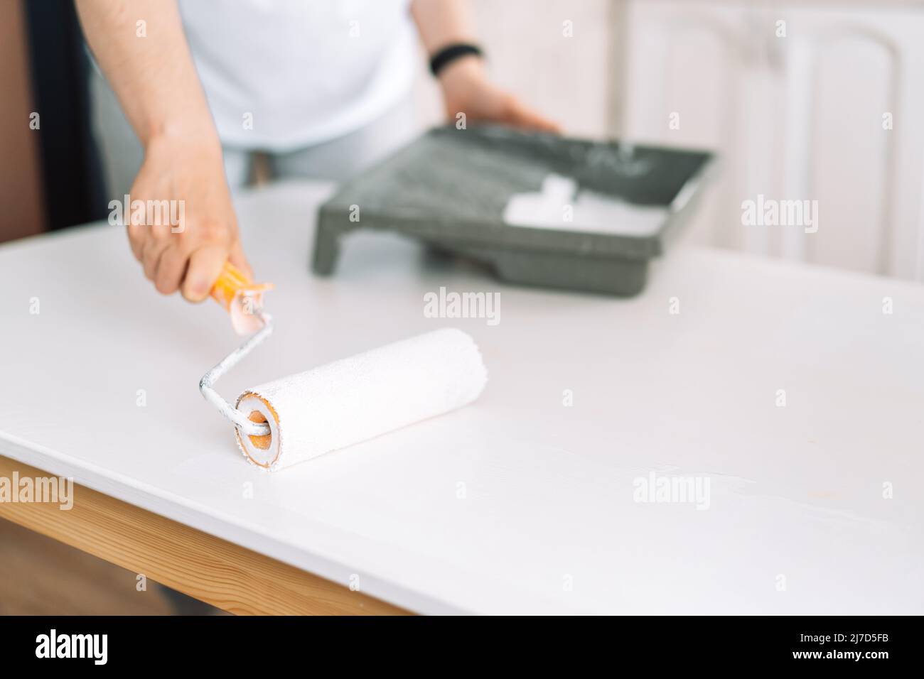Painting wooden table with roller in white Stock Photo - Alamy