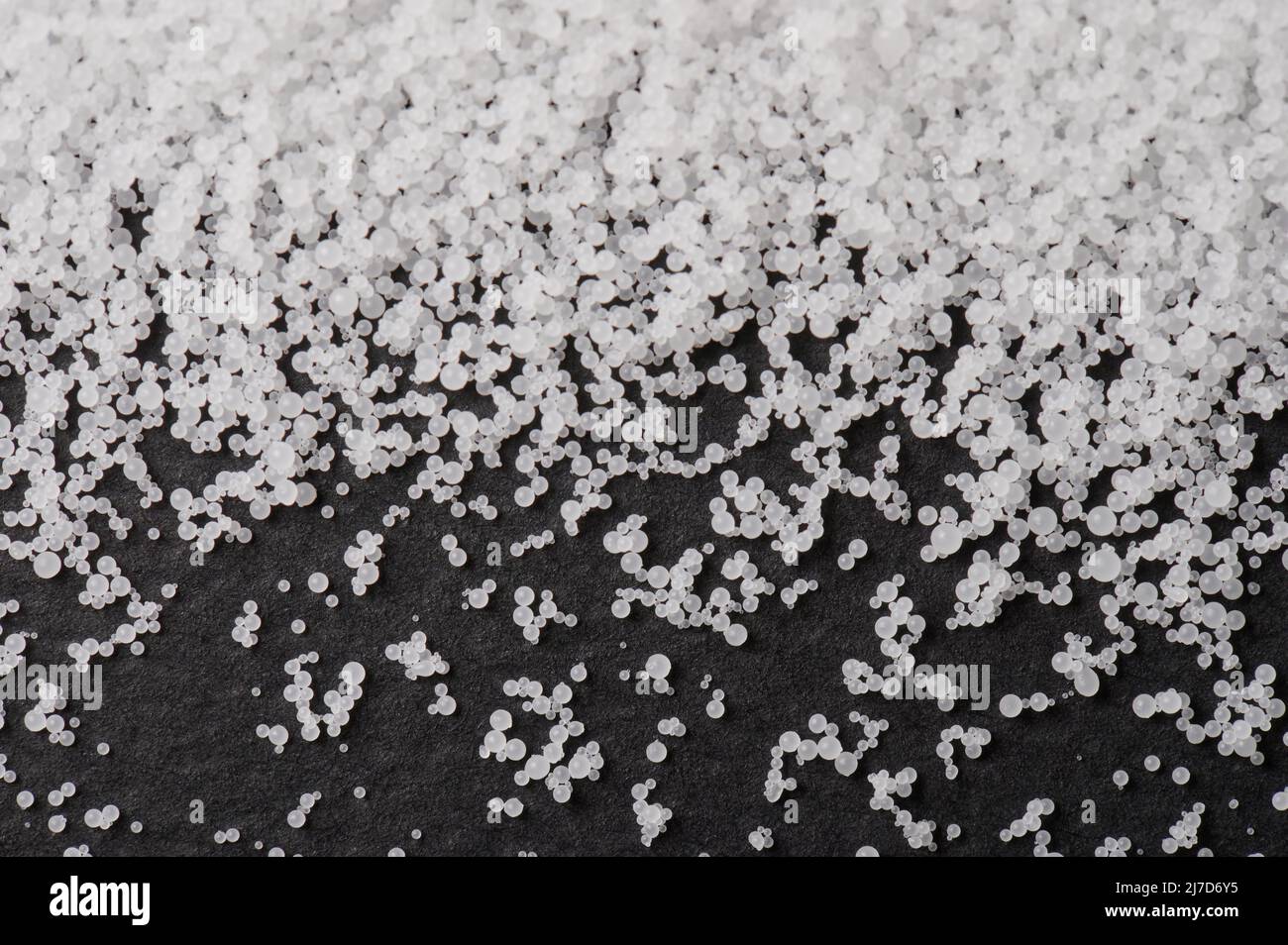 White many polymer granules on black matte background Stock Photo - Alamy