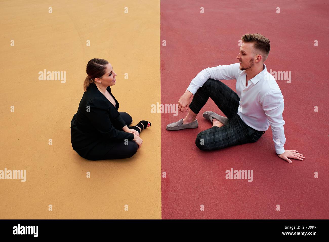 Two business people talking while sitting on floor outdoors Stock Photo ...
