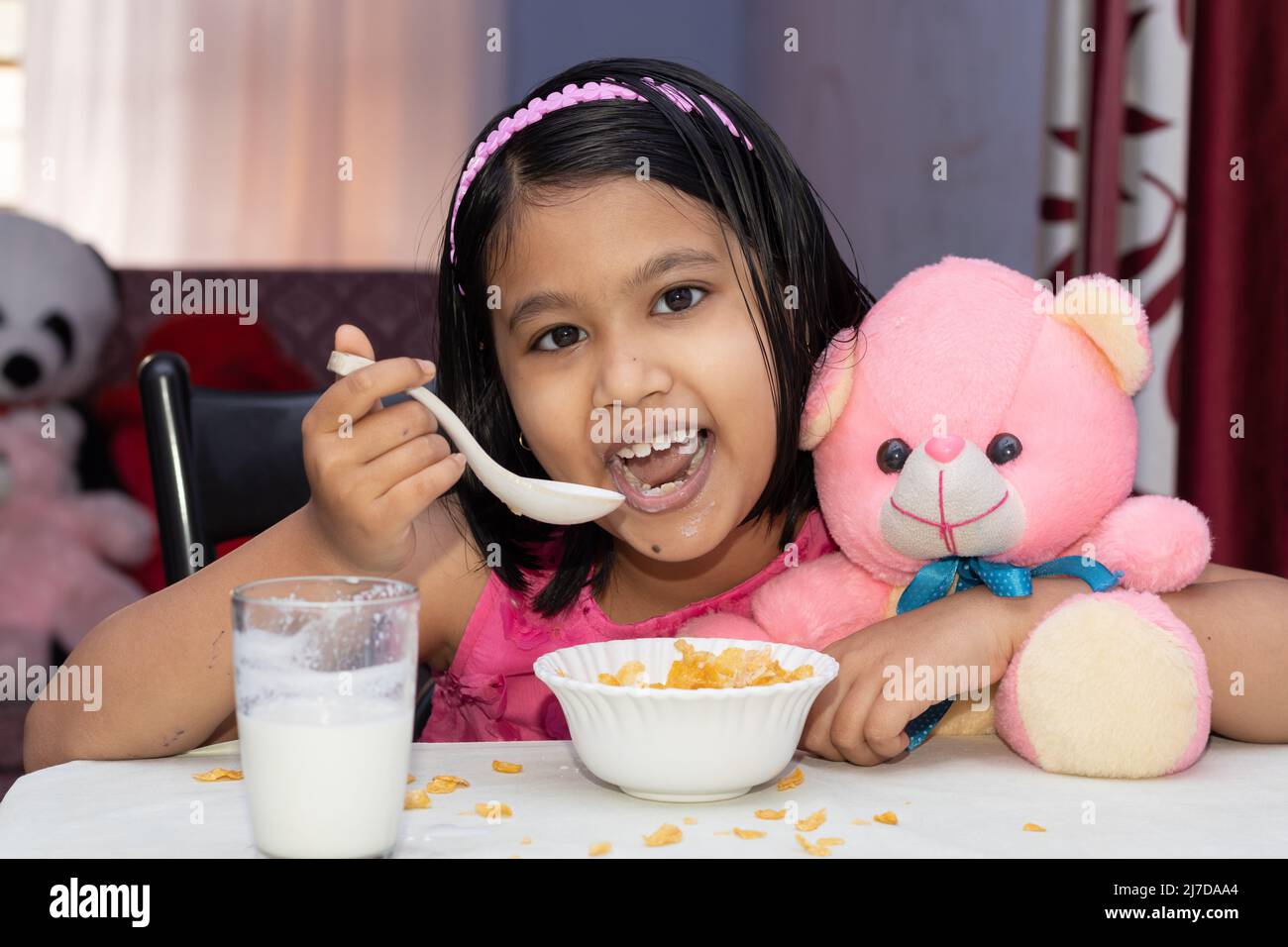 An Indian girl child eating cereal with milk with smiling face and ...