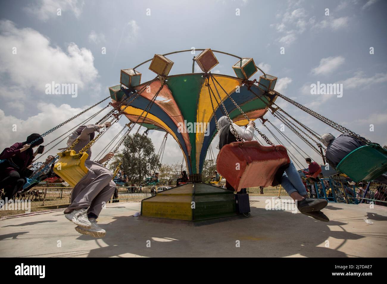 Palestinians enjoy a swing ride in the amusement park during the Eid al ...