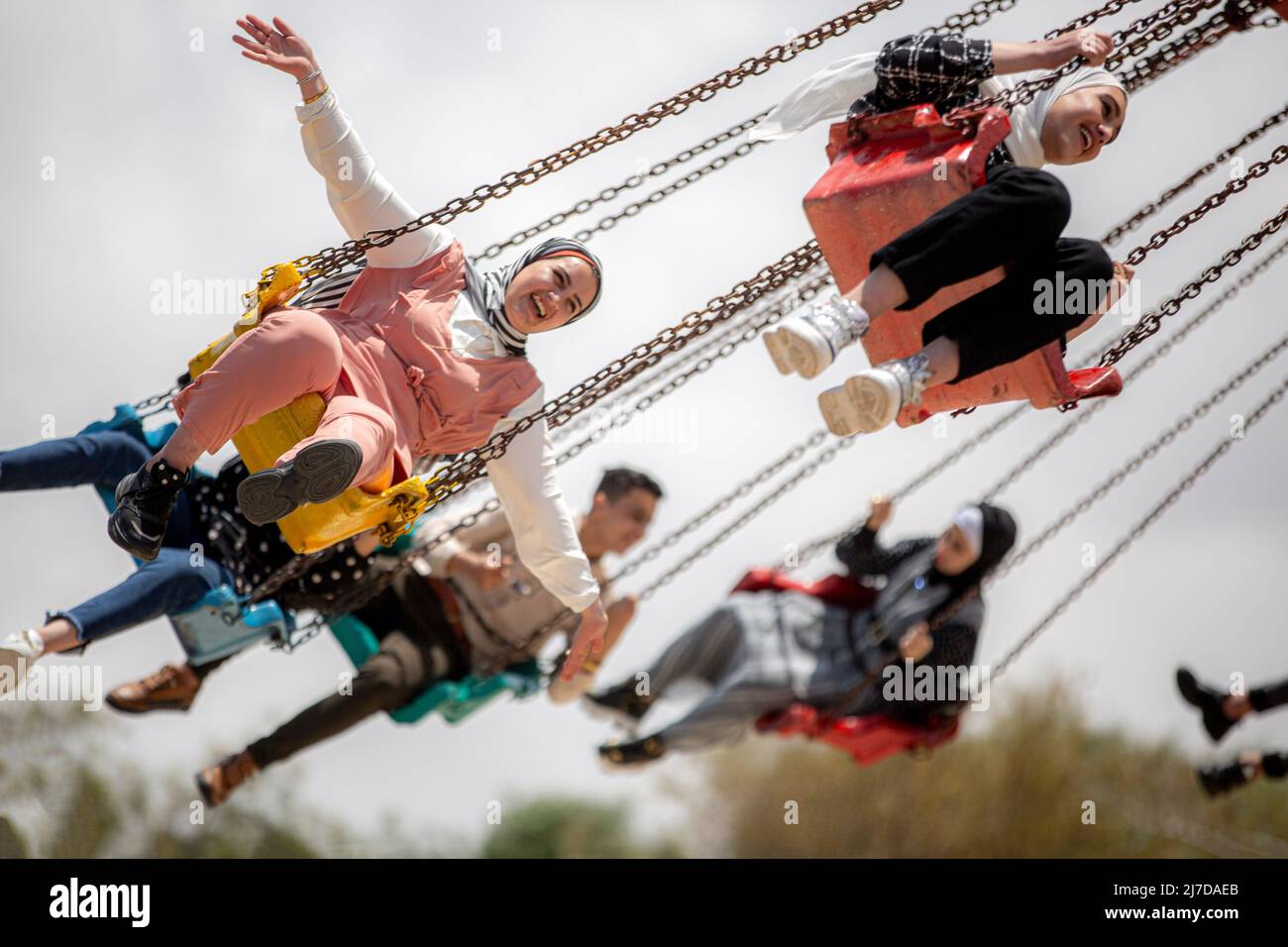 Palestinians enjoy a swing ride in the amusement park during the Eid al ...