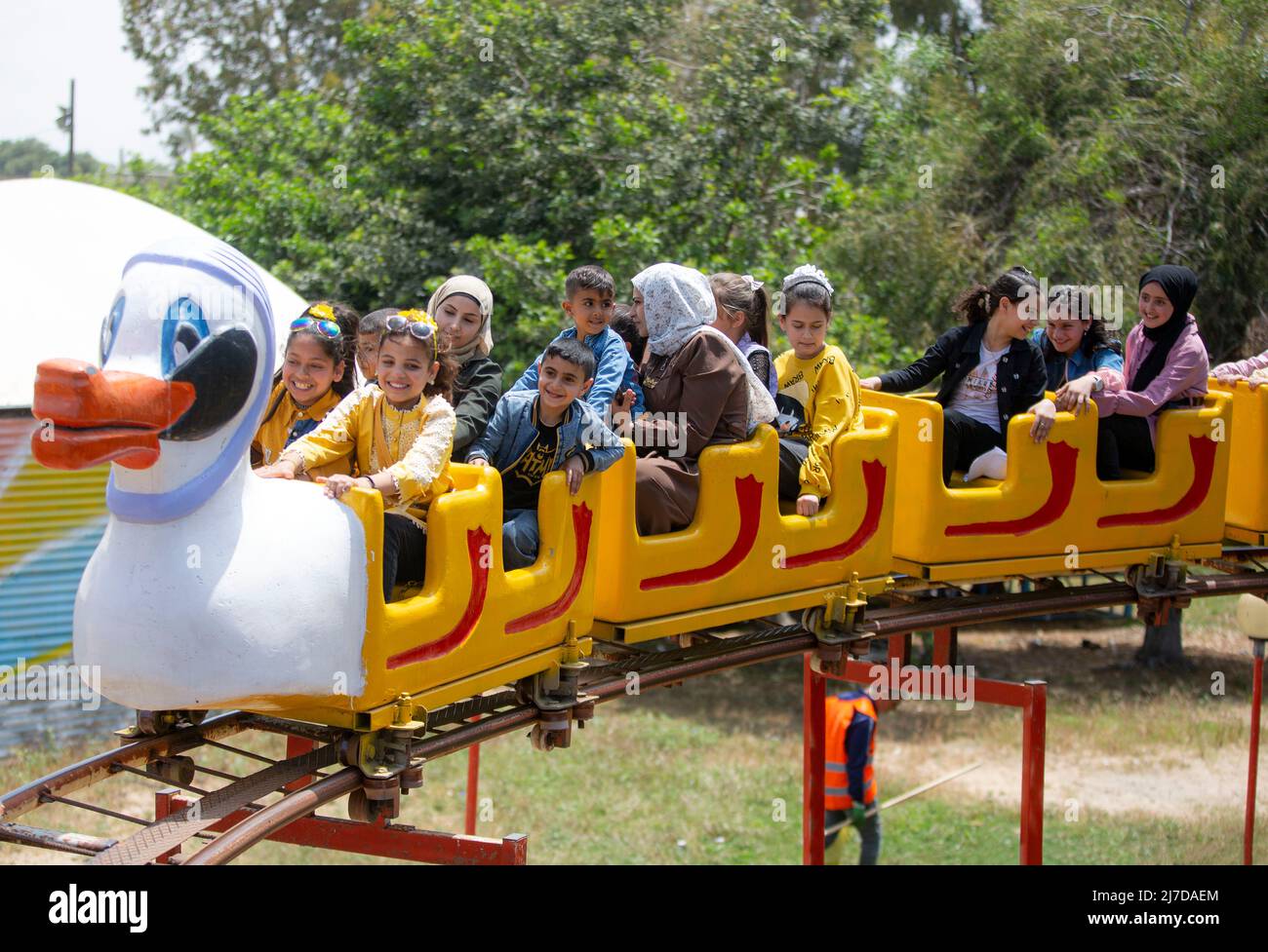 Palestinians enjoy a swing ride in the amusement park during the Eid al ...