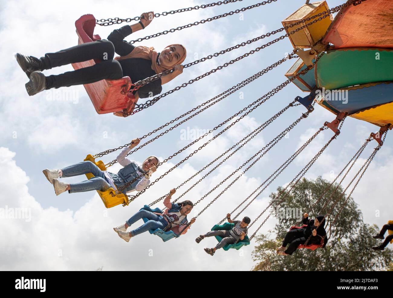 Palestinians enjoy a swing ride in the amusement park during the Eid al ...