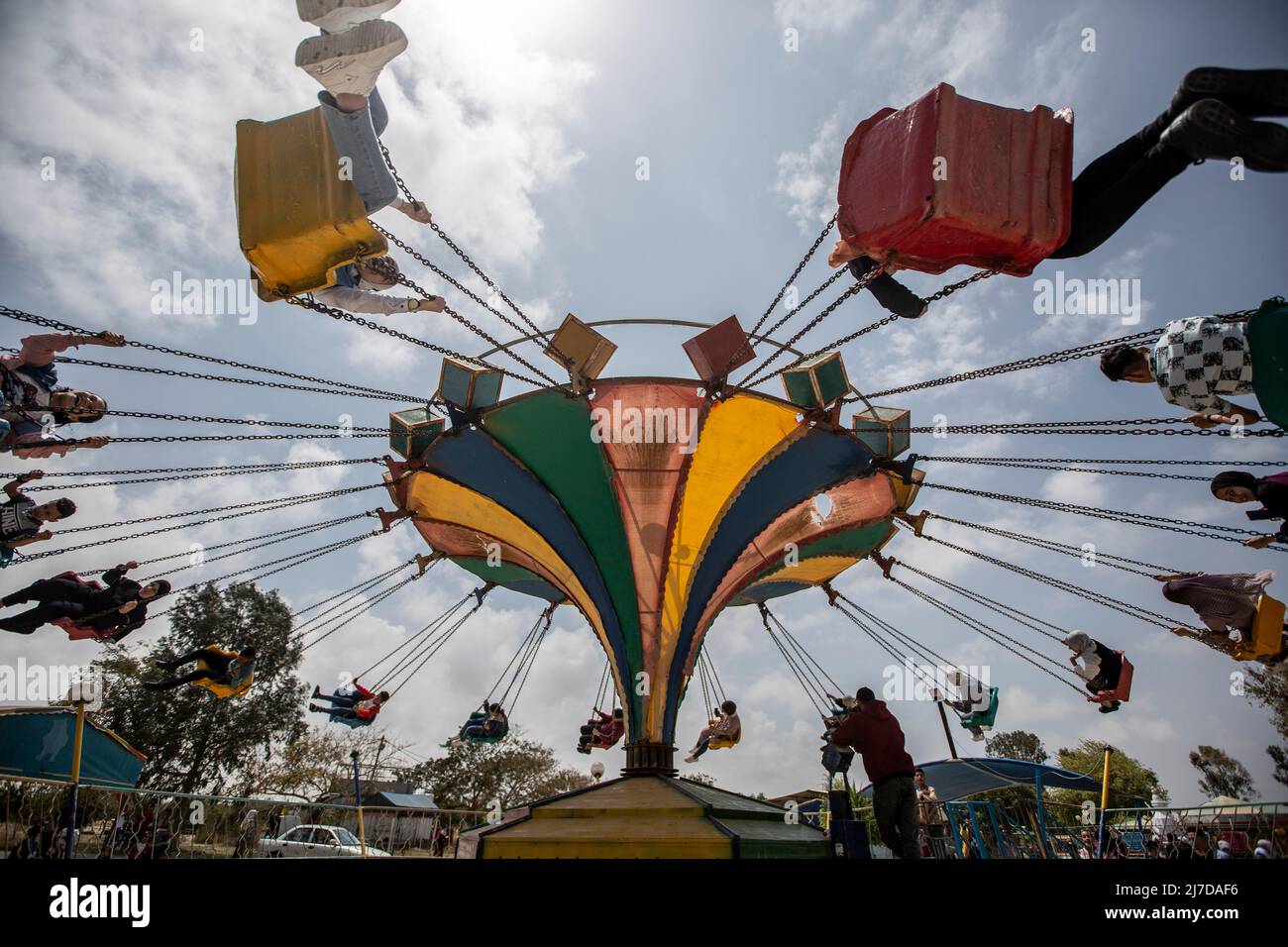 Palestinians enjoy a swing ride in the amusement park during the Eid al ...