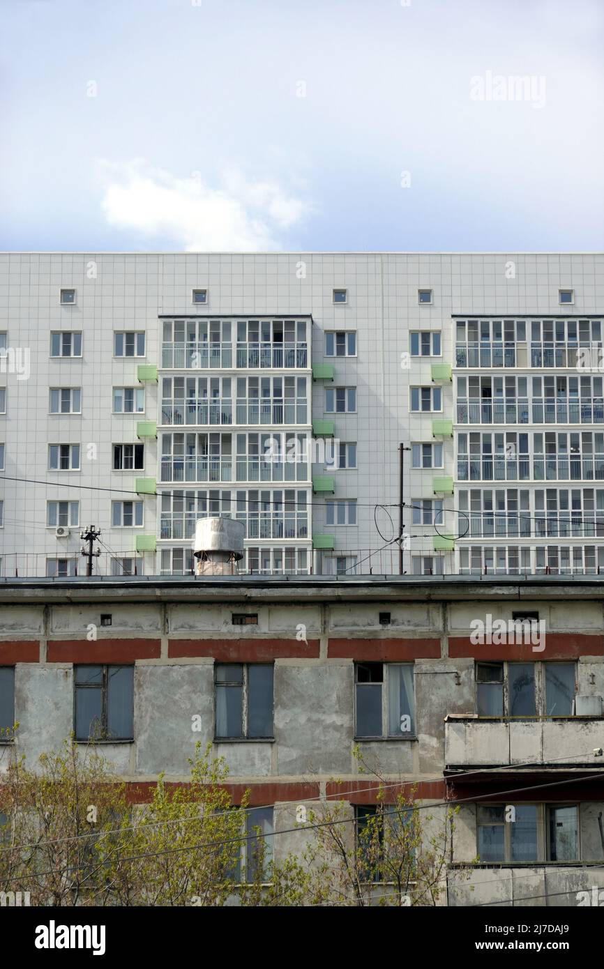 Old dilapidated house and new dwelling block of flats vertical photo ...