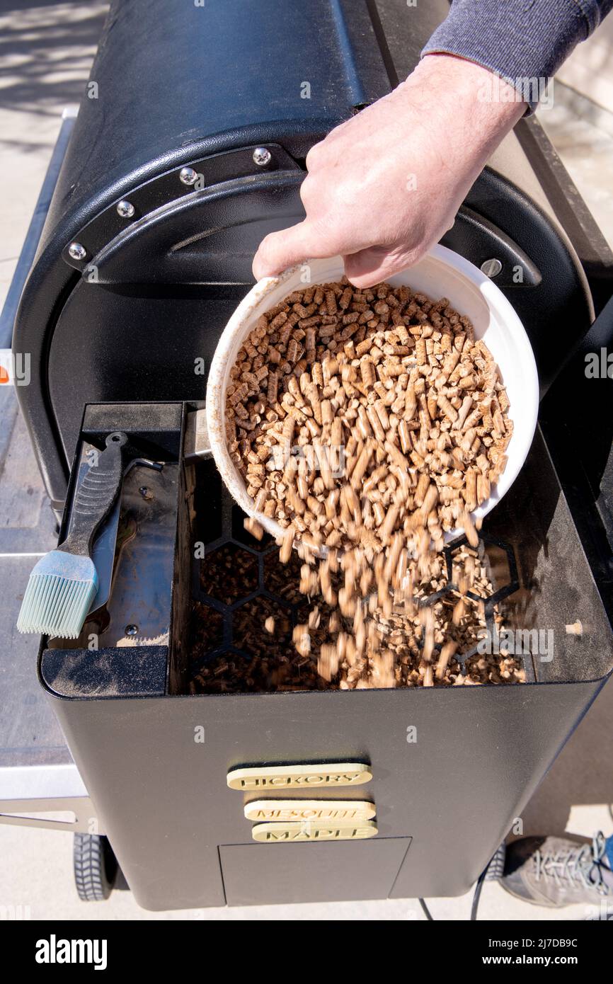 Backyard smoker with a pit boss pouring hardwood pellets in Stock Photo ...