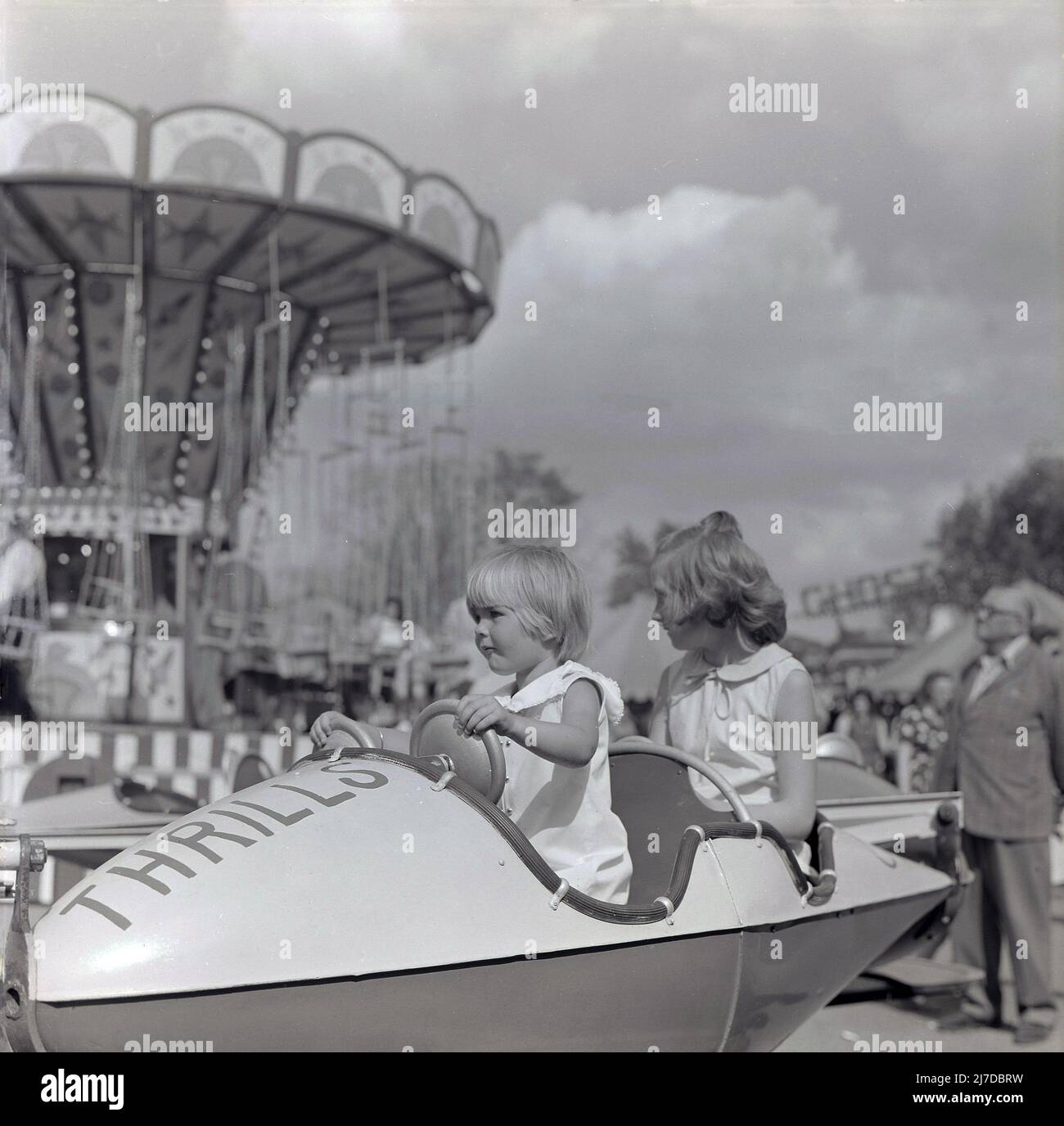 1960s, historical, two young girls sitting in an amusement ride at a ...