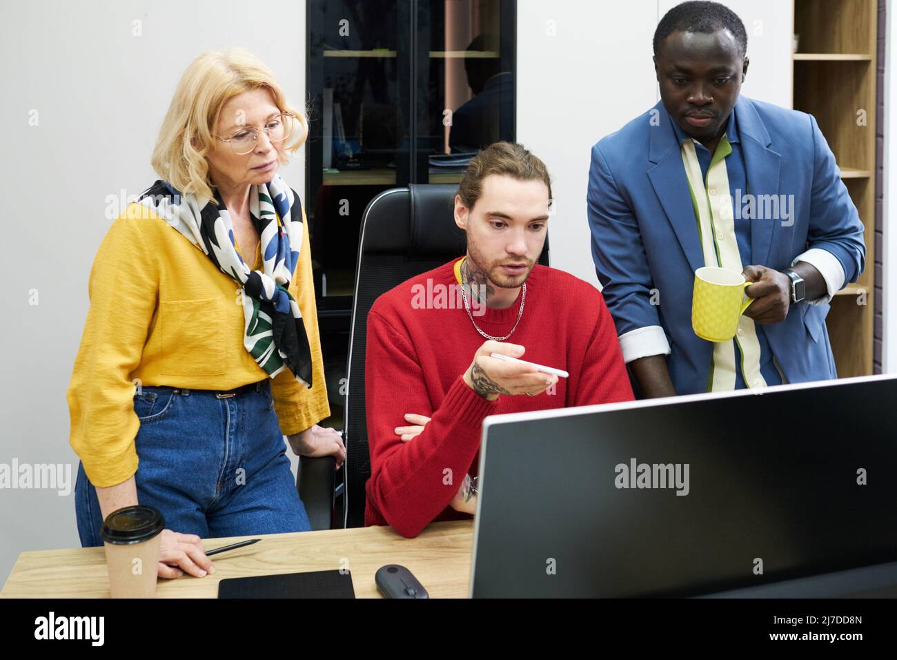 Group of graphic designers looking at computer monitor and discussing ...