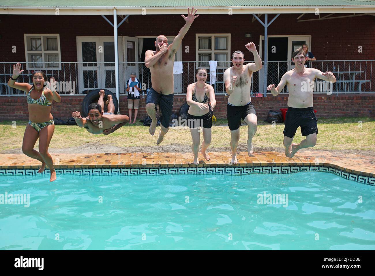 Six students mid-air jumping into the pool at the GSB team-building ...