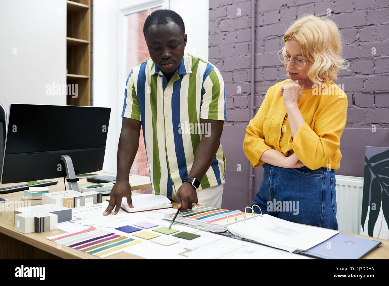 Two designers choosing colour in palette at table and discussing new ...