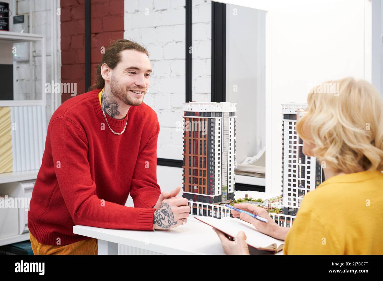 Young architect smiling during conversation with businesswoman, they ...
