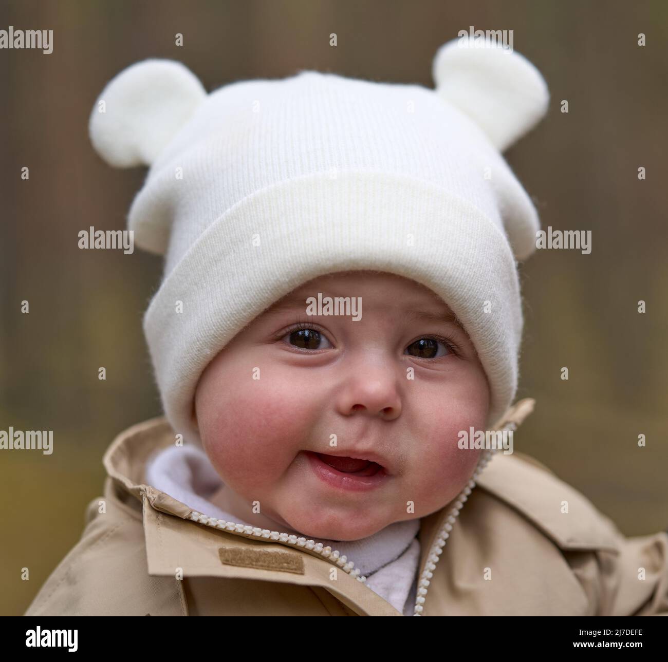 Cute brown eyed baby girl portrait close-up. She wearing cap with the ... Cute brown eyed baby girl portrait close-up. She wearing cap with the ...