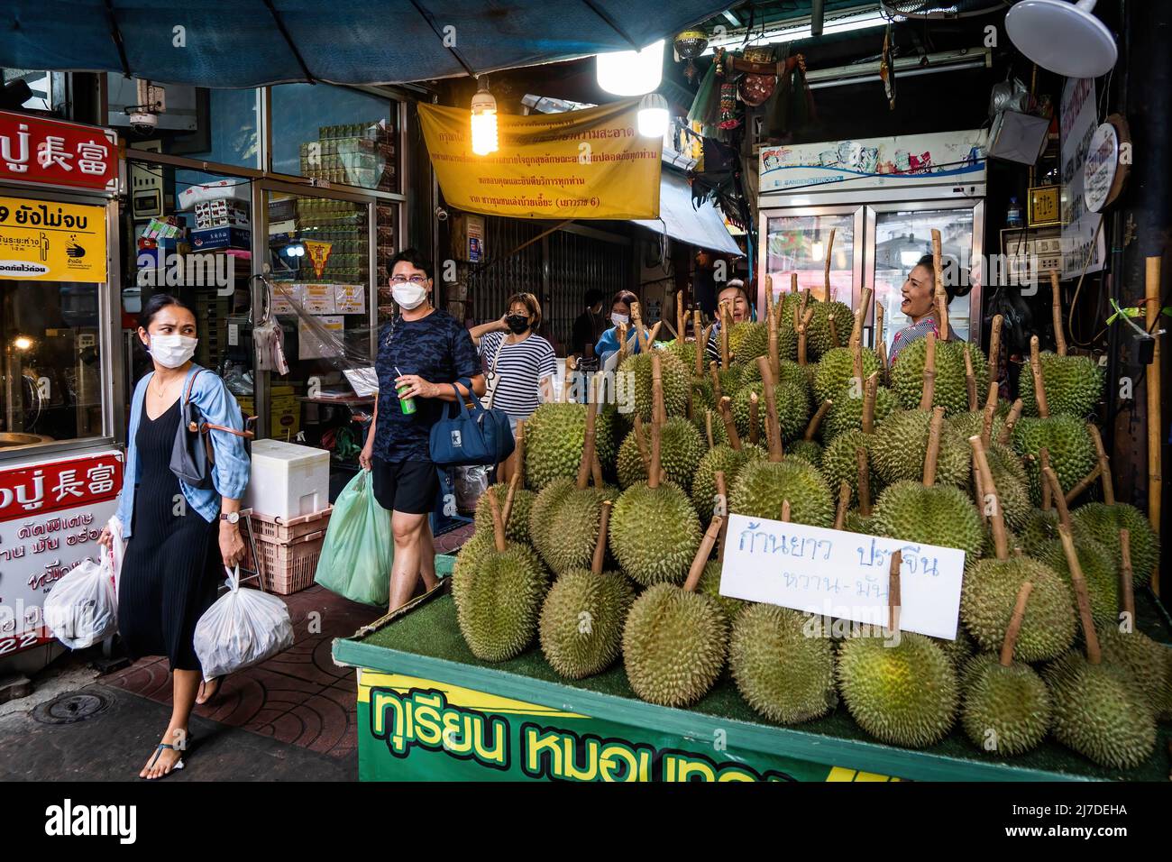 People walk past durian fruit for sale at an outdoor market in ...