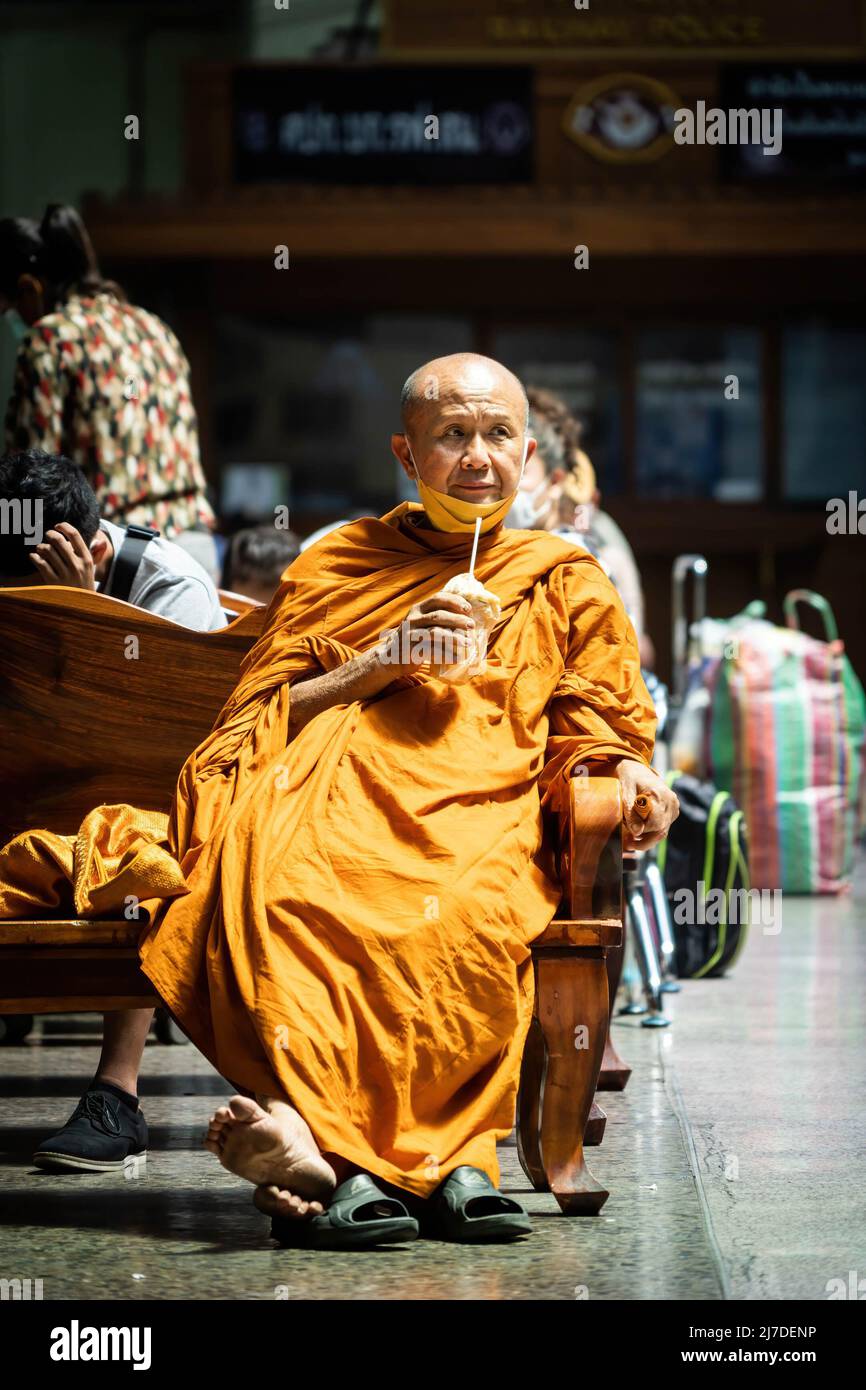 A monk has coffee while waiting for a train at Hua Lamphong, also known ...