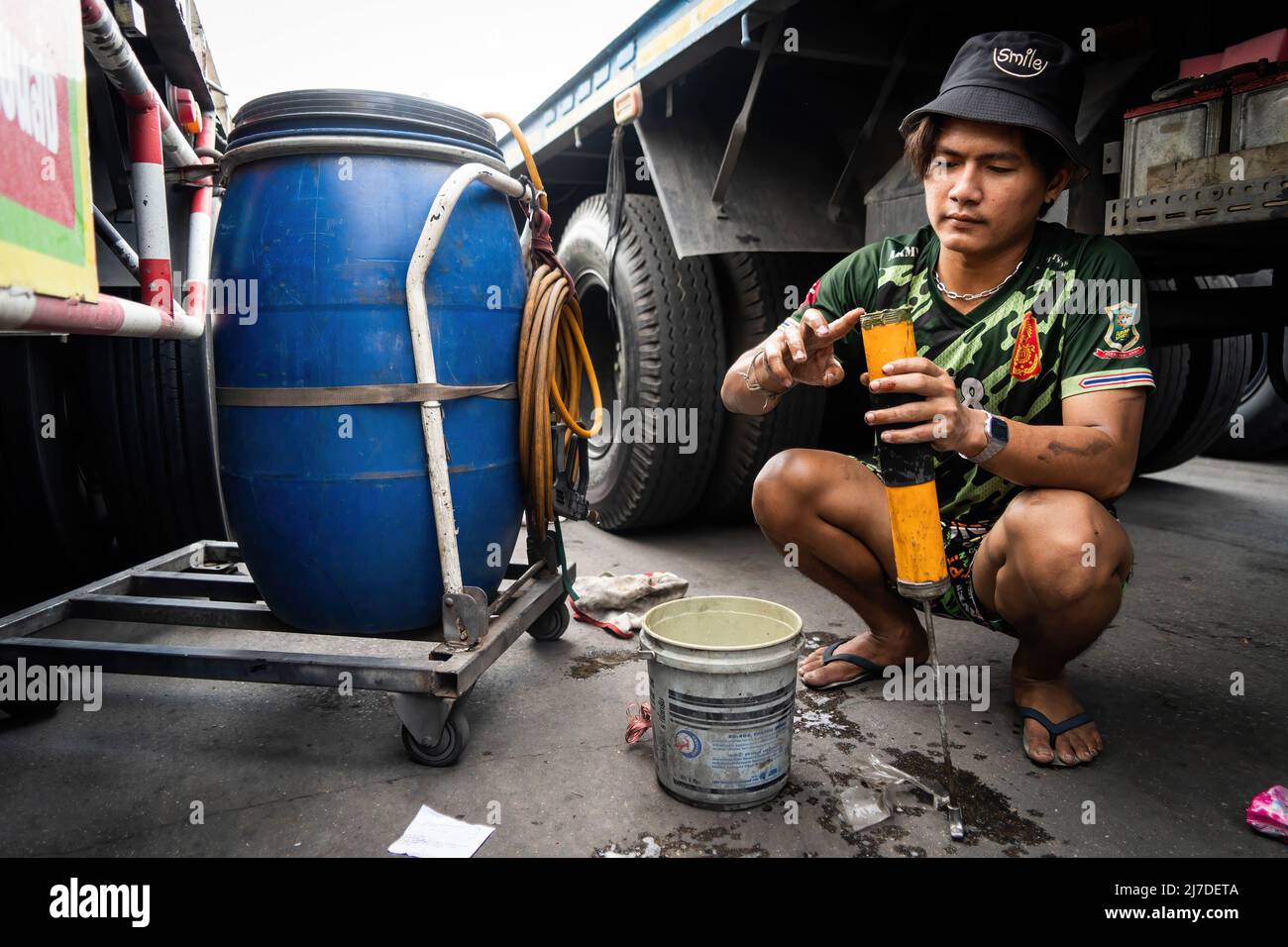 A mechanic makes glue while repairing a large long-haul truck. Thailand ...