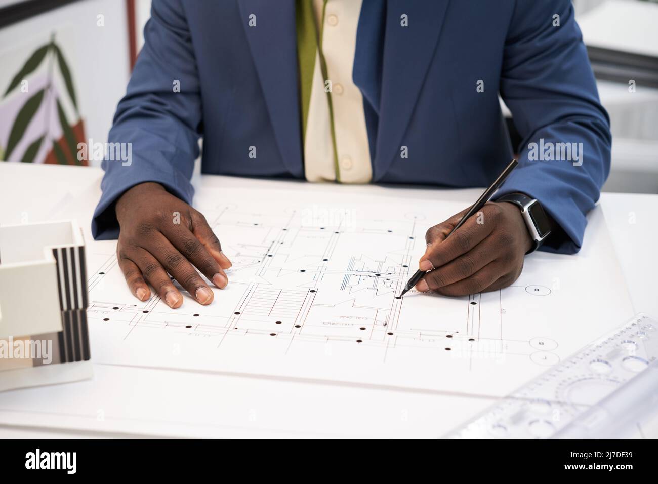 Close-up of African architect using pencil and ruler to draw project of ...