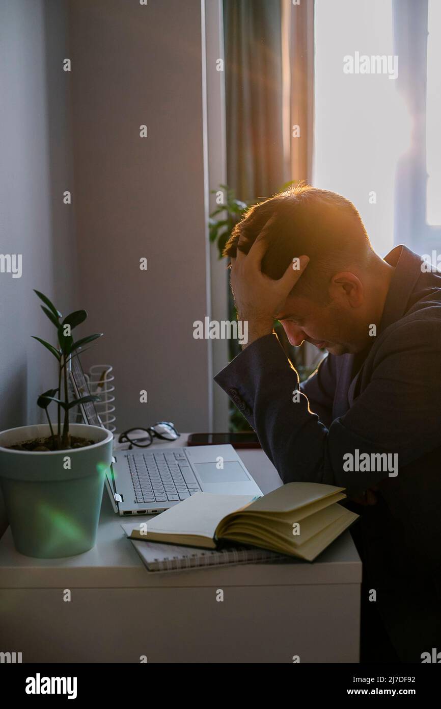 Upset man sitting at office table and looking at laptop screen, touch ...