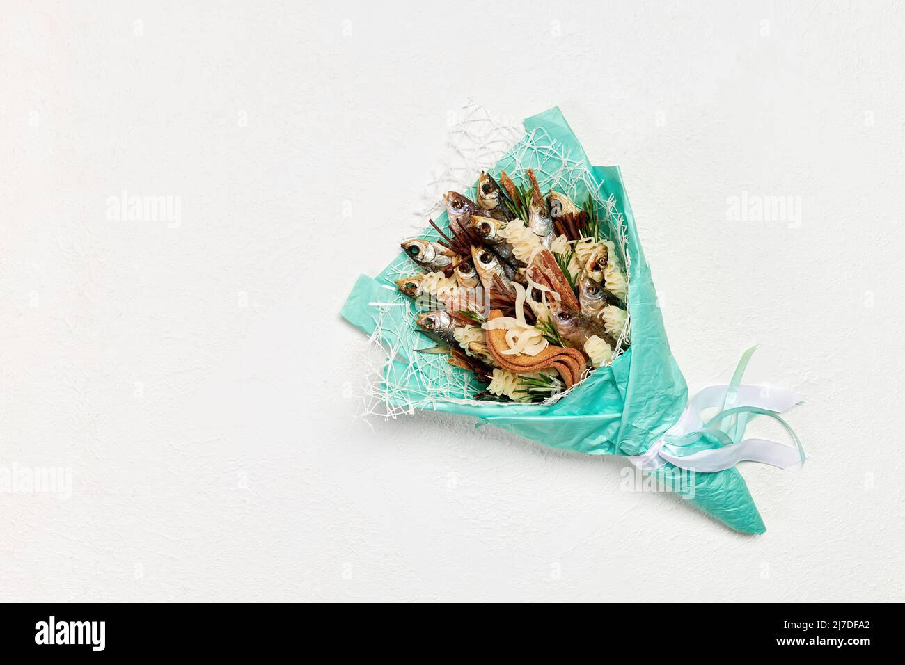 Turquoise bouquet made of dried fish and snacks on a white background ...