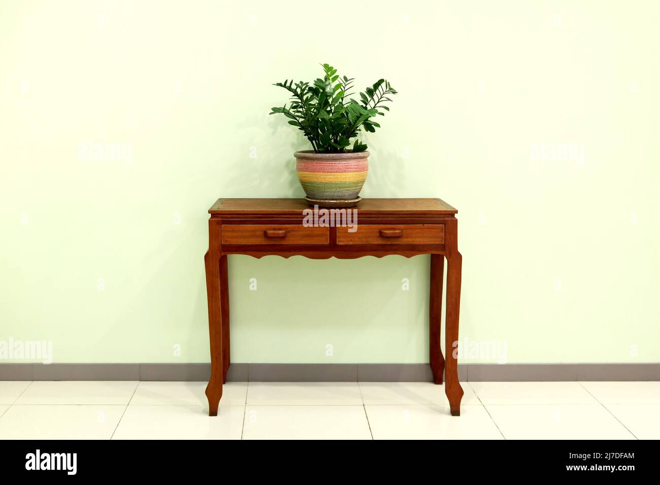 Flower in the pot stands on a wooden table against the background of ...